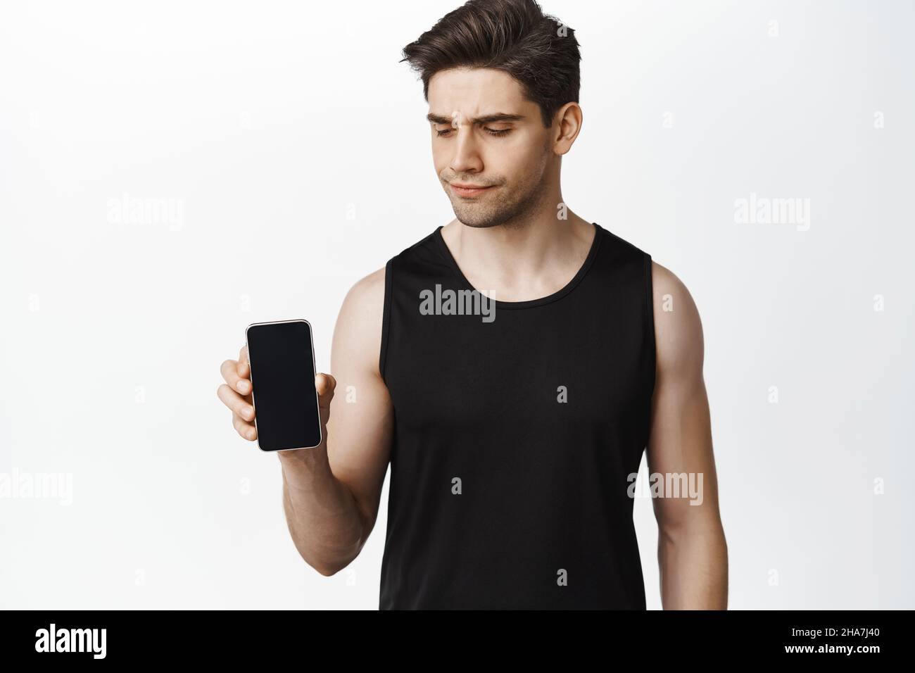 Portrait of man looking doubtful at smartphone screen, showing app with ...