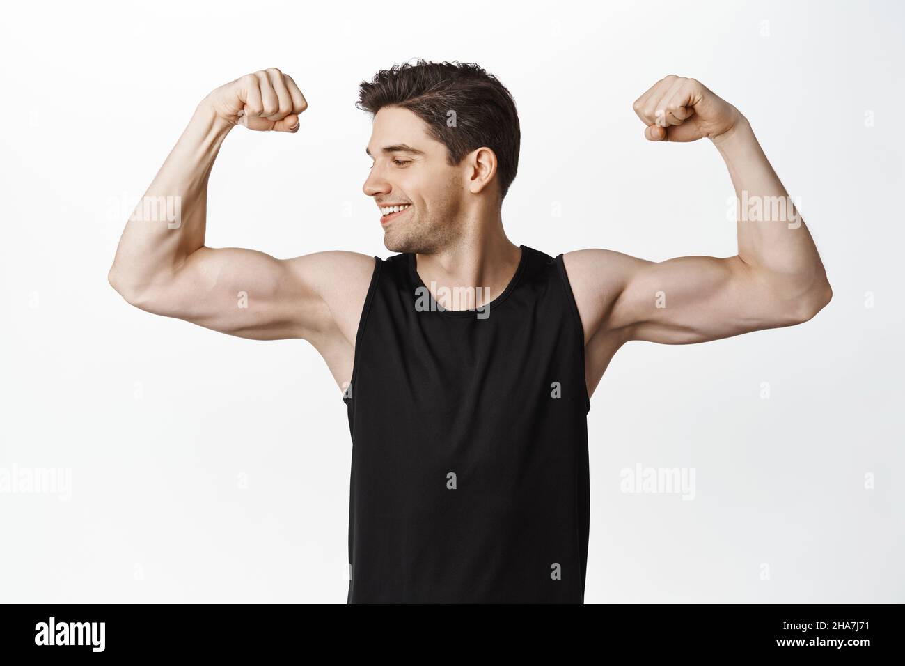 Portrait of male athlete, smiling sportsman flexing biceps, looking ...