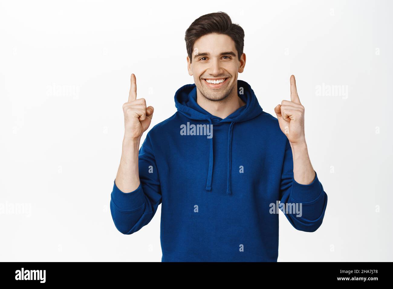 Portrait of smiling caucasian man with happy face, pointing fingers up ...