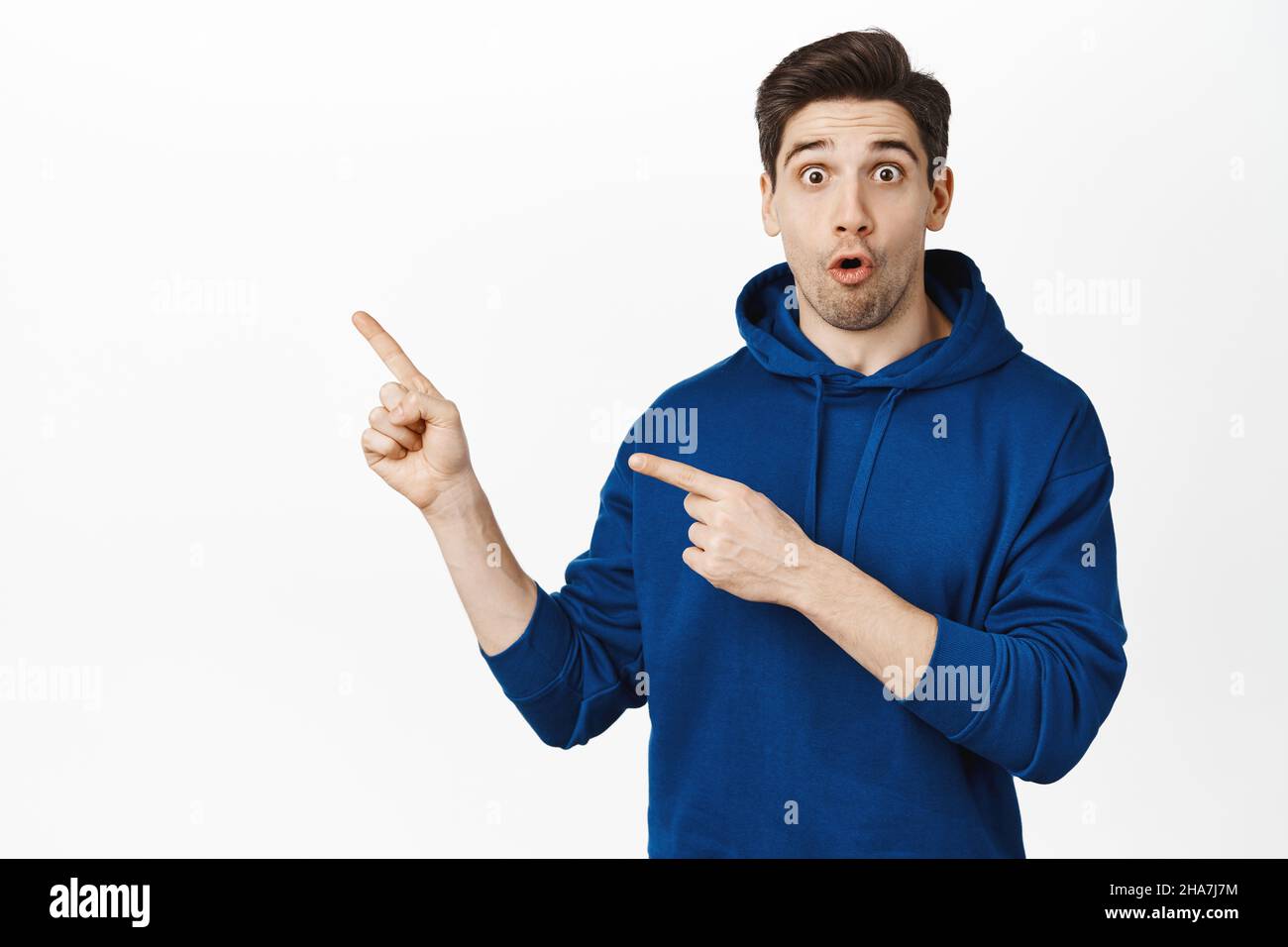 Portrait of surprised guy say wow, pointing fingers left at promo ...