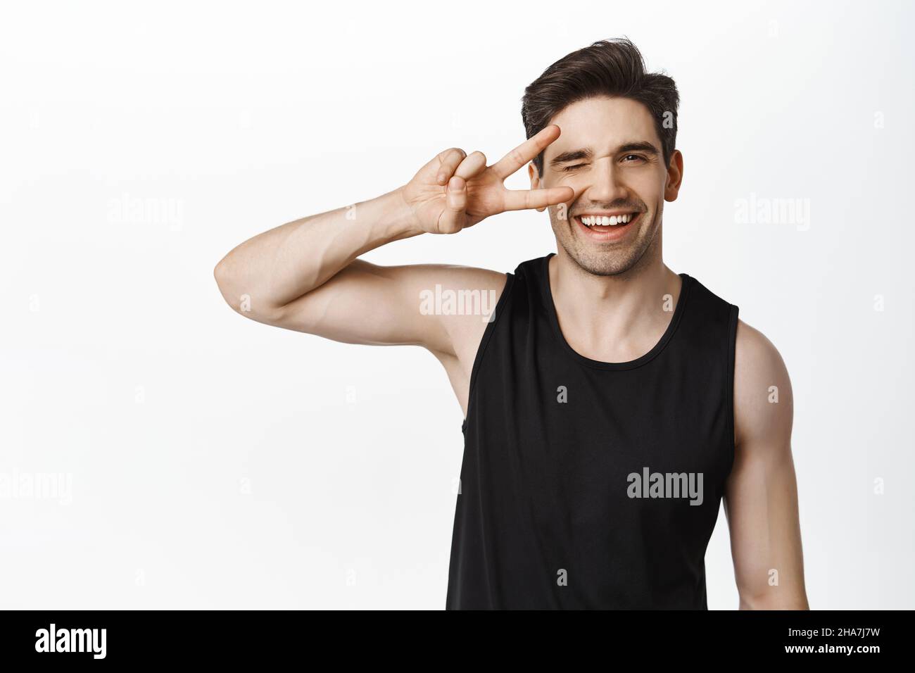 Happy healthy man in sport uniform showing peace sign and smiling ...