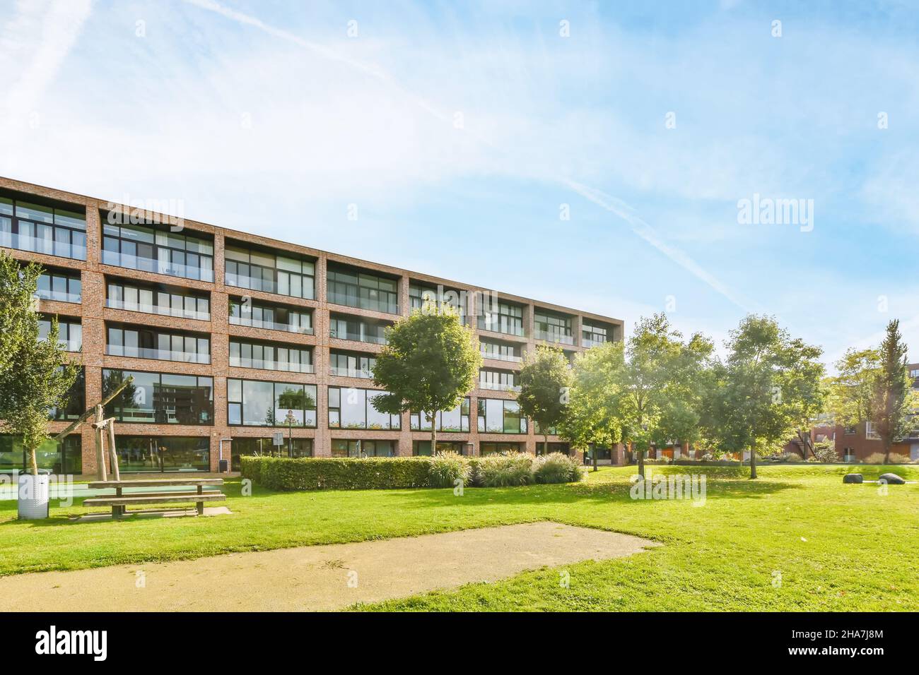 Stunning view of the building with huge windows and a fresh lawn next ...
