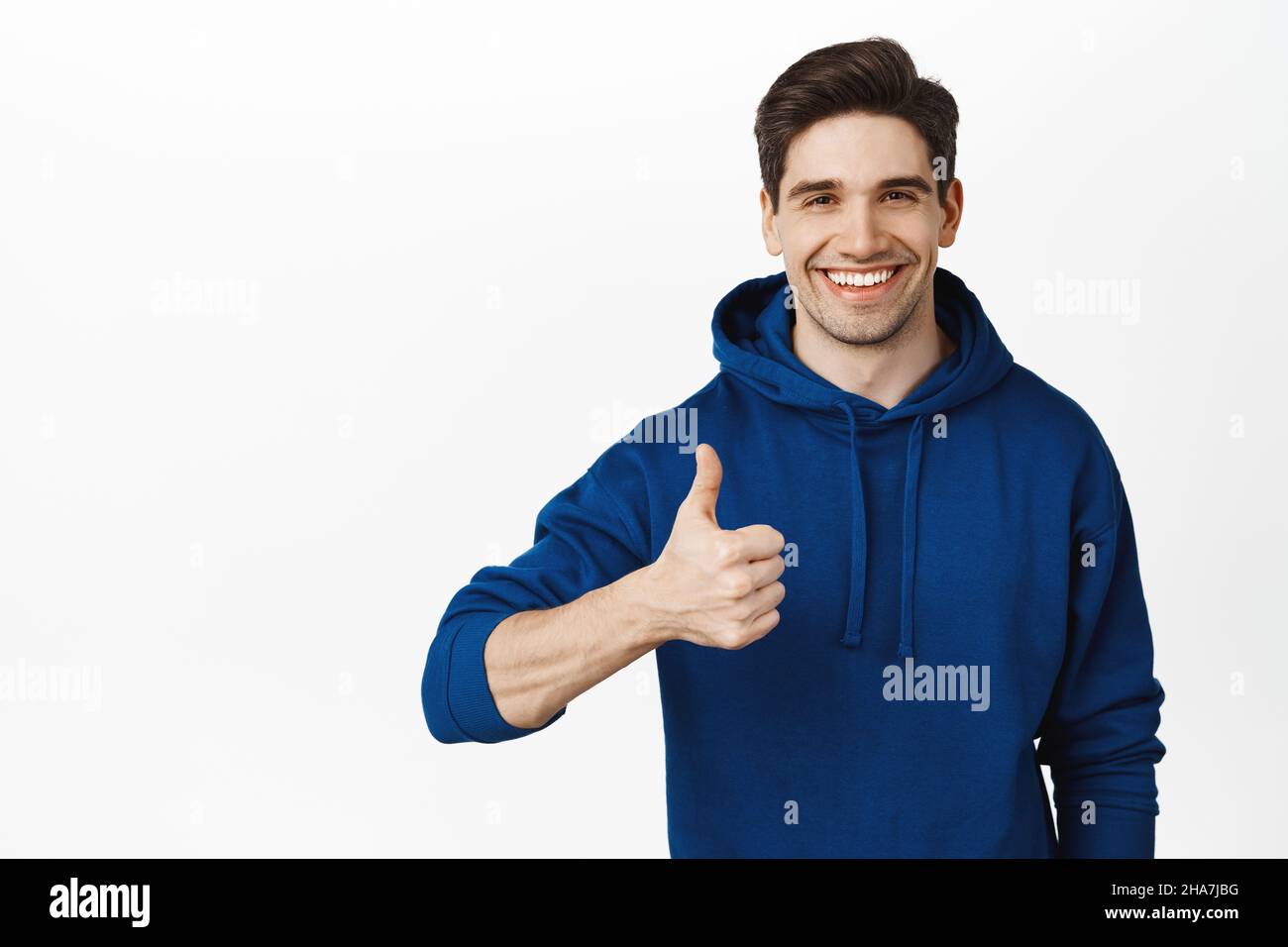 Very good. Smiling confident male model shows thumbs up and look ...