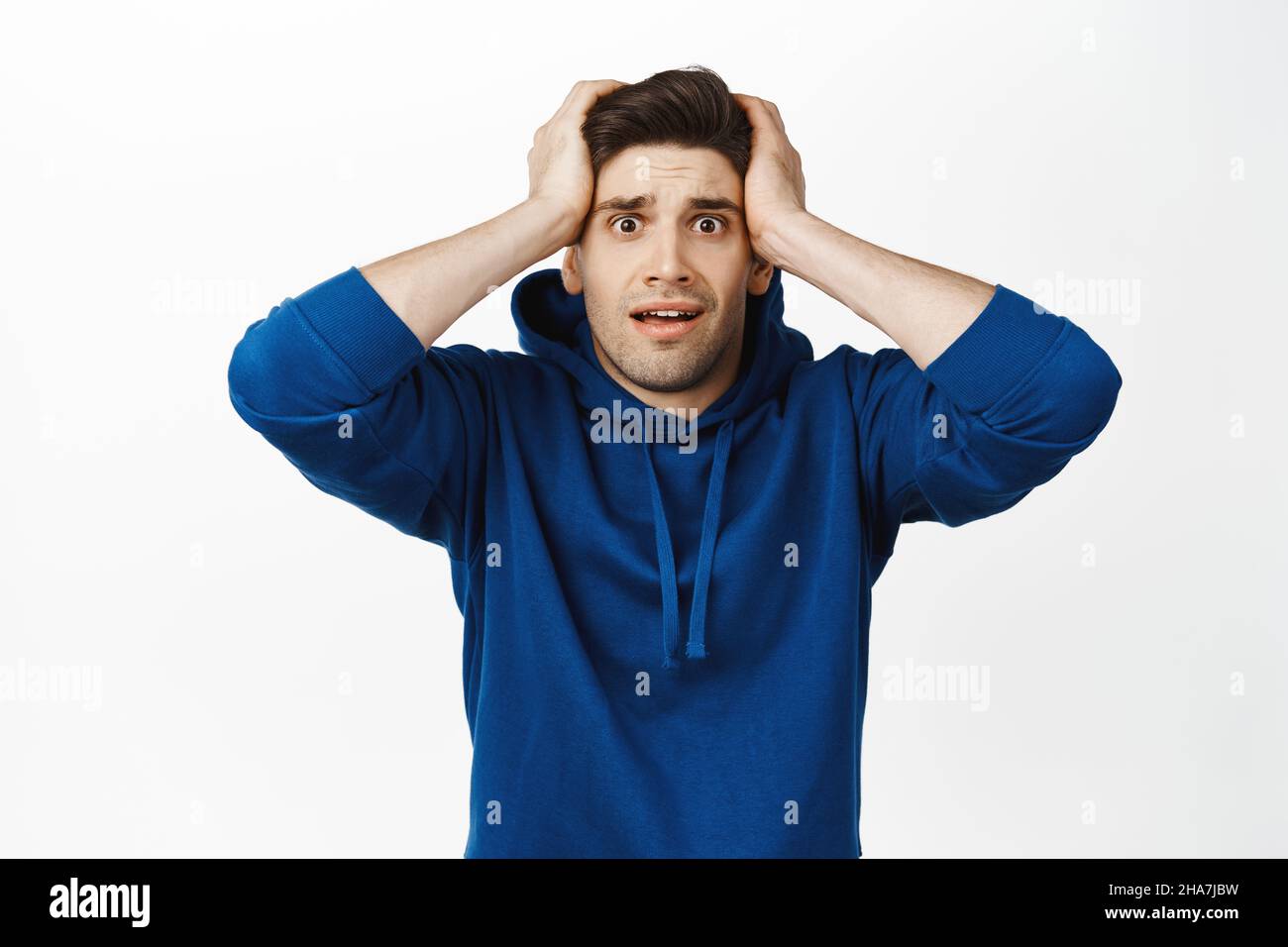Shocked and scared man, boyfriend grab his head and looking in panic ...