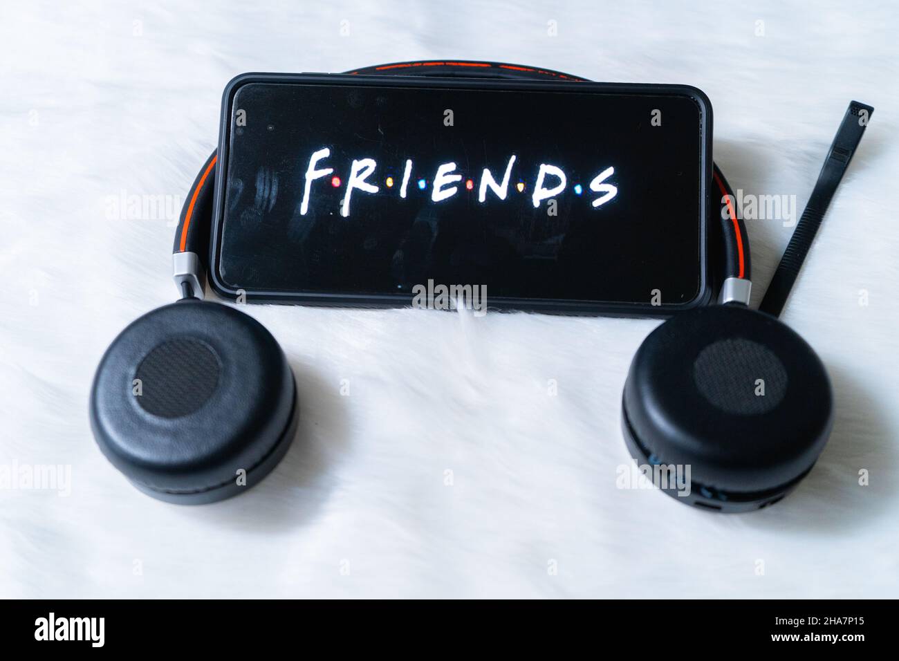 mobile smartphone on stand with headphones near it placed on a fur snow ...