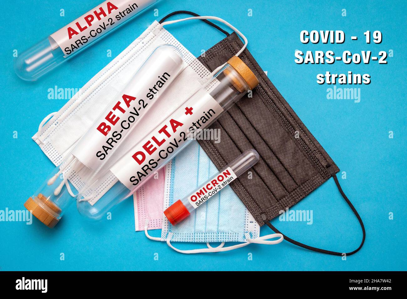 Pile of medical face masks with test tubes of different SARS-CoV-2 ...