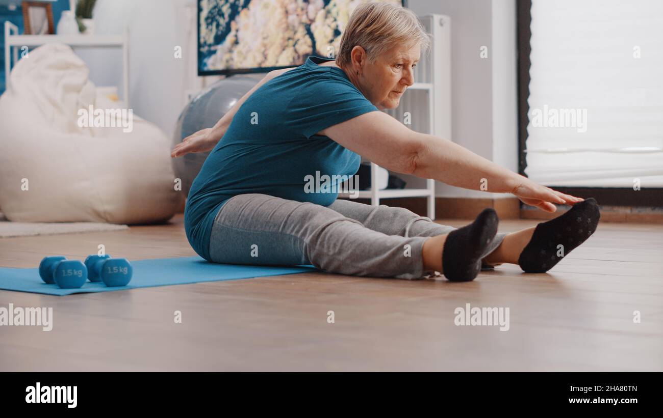 Close up of pensioner doing physical exercise to stretch muscles at ...