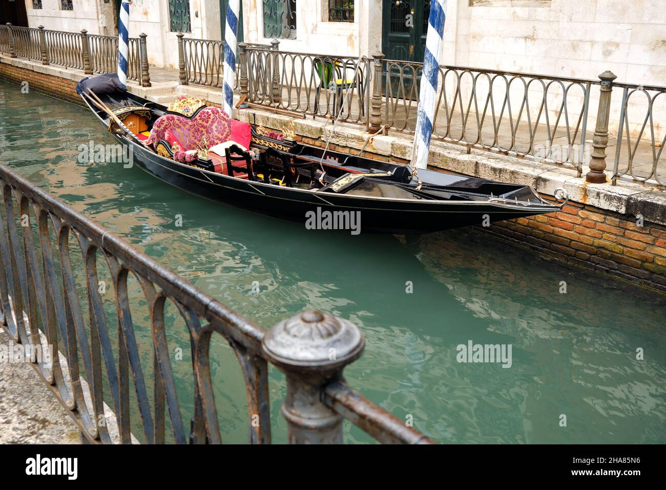 Traditional Venetian gondola moored in water canal in the historic city ...