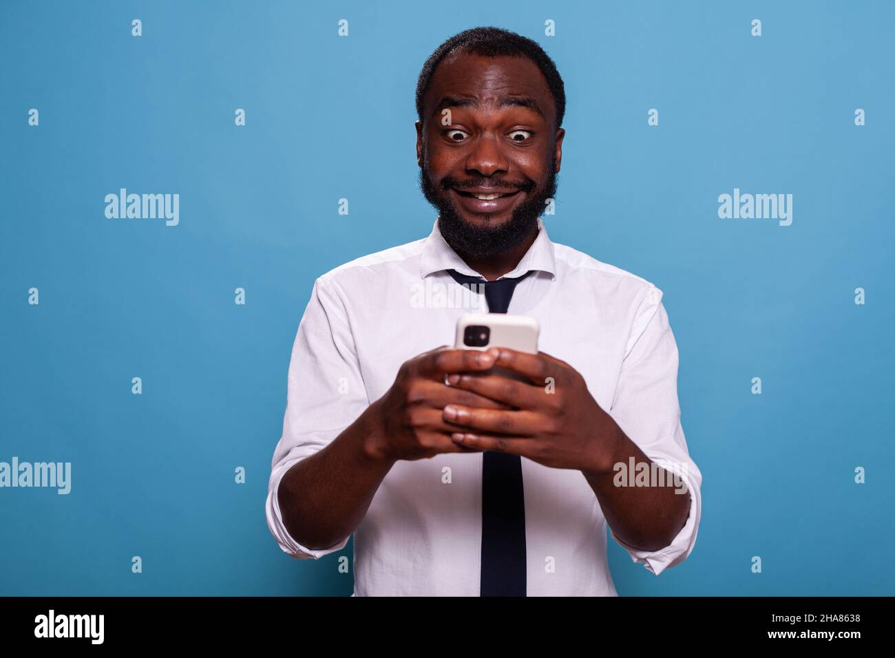 Portrait of businessman holding mobile phone playing exciting new ...
