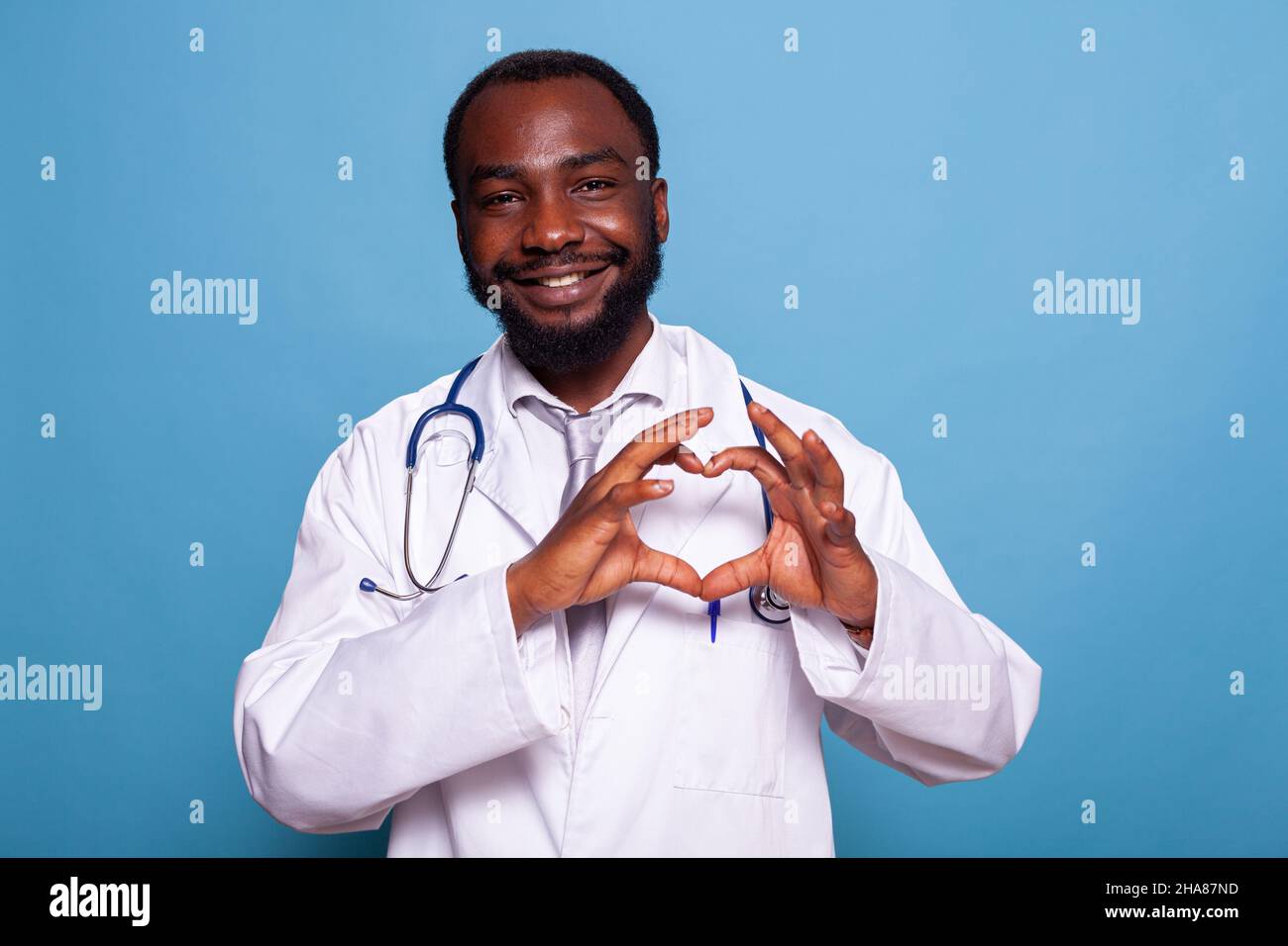 Smiling cardiology doctor making heart shape with hands to show care ...