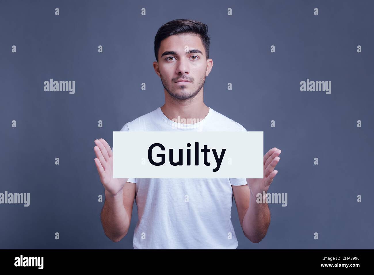 Man holding sheet of paper with text guilty Stock Photo - Alamy