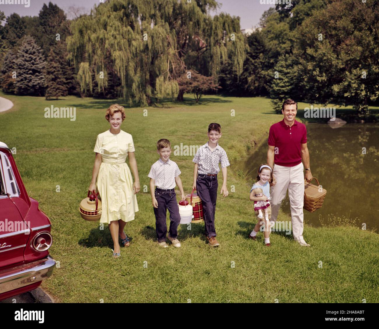1960s FAMILY OF FIVE GOING ON A PICNIC WALKING TOWARD AND LOOKING AT ...