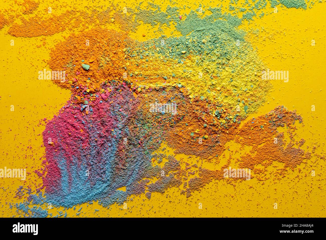 Mixture of multicolored powder is scattered randomly on a yellow ...