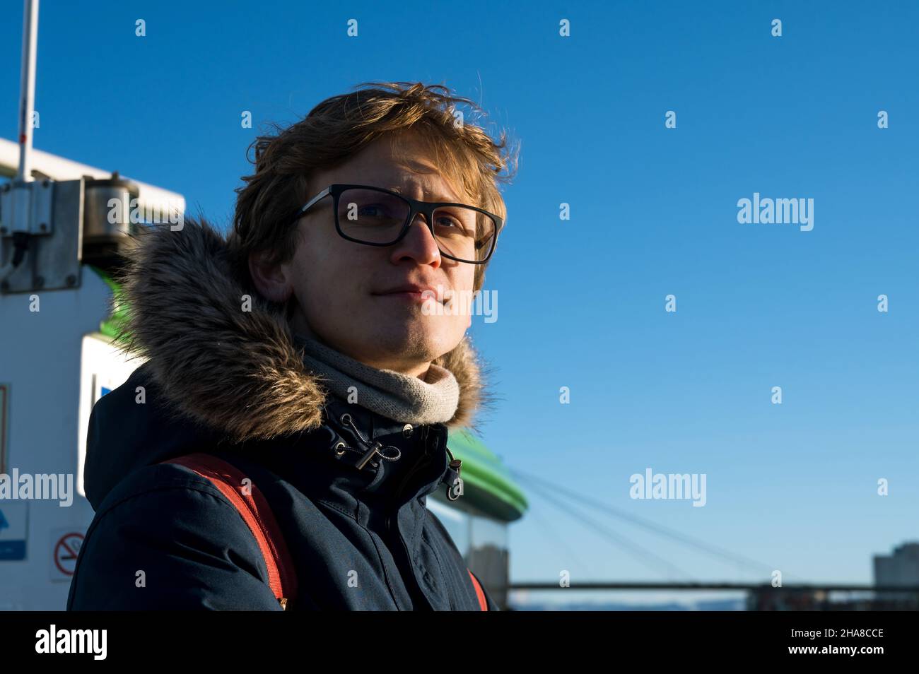 Portrait of young handsome man in glasses and coat. A modern ship in ...