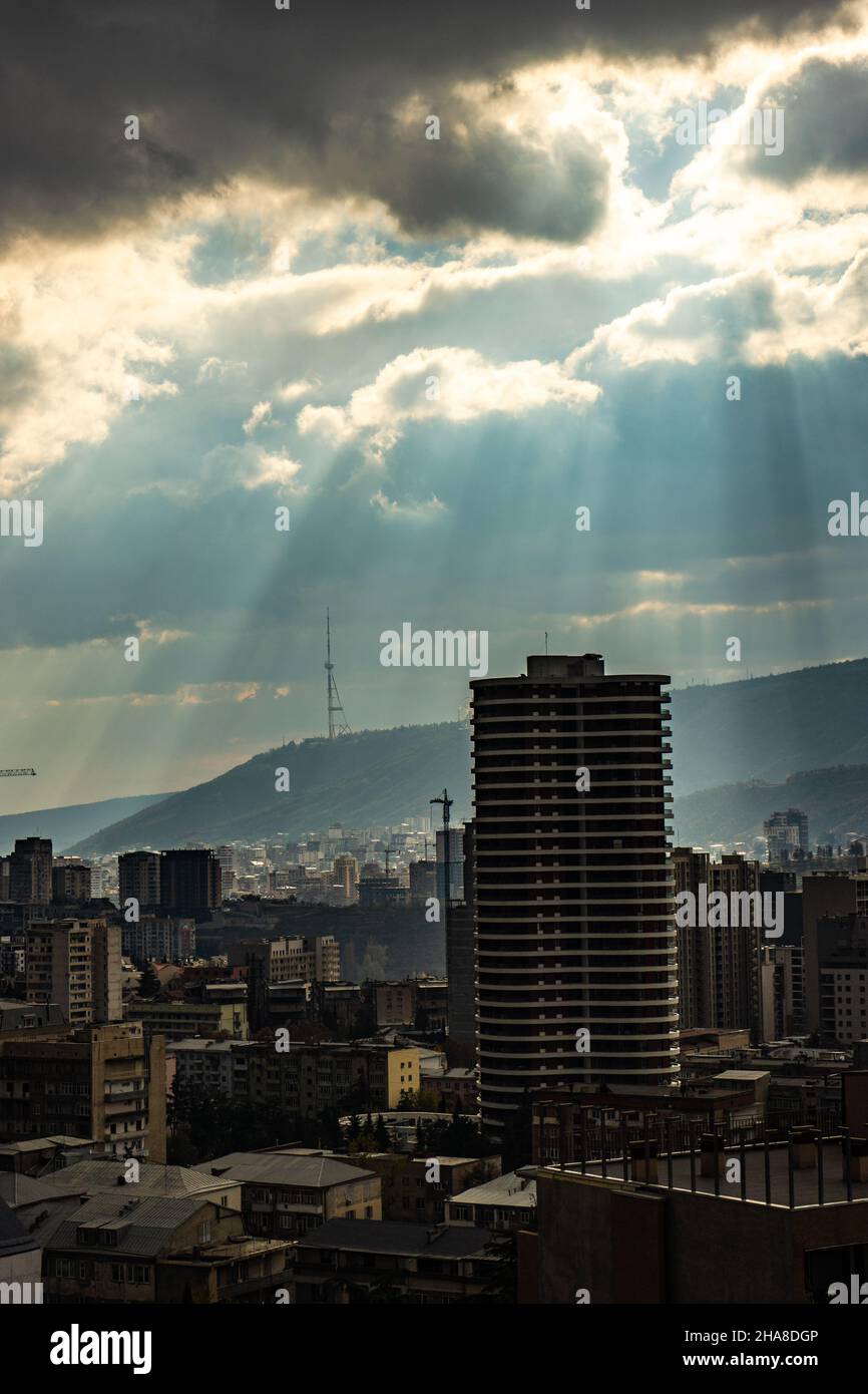 Dramatic sky over Tbilisi city's downtown in late autumn with sun rays ...