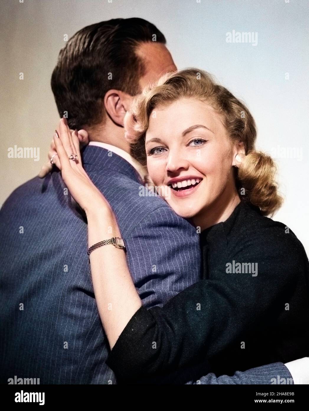 1950s COUPLE ARM IN ARM EMBRACE HUG MAN FACE HIDDEN BY WOMAN SMILING ...
