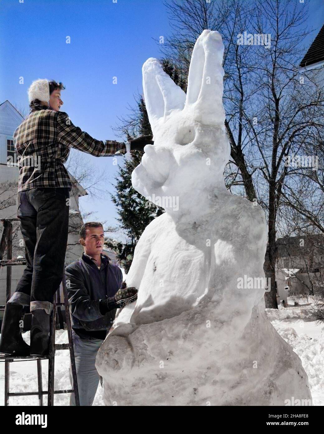 1950s COUPLE MAN AND WOMAN OUTSIDE IN WINTER SCULPTING GIANT SNOW BUNNY ...