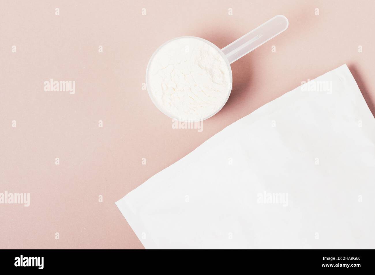 Protein powder in scoop next to paper bag on light brown background ...