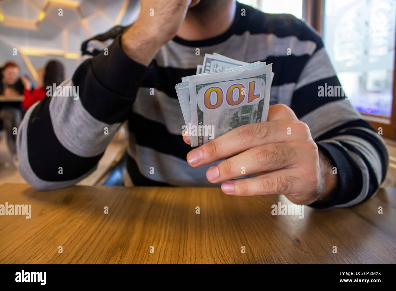 Man hand holding dollar bills while sitting in a cafe. He's trying to ...
