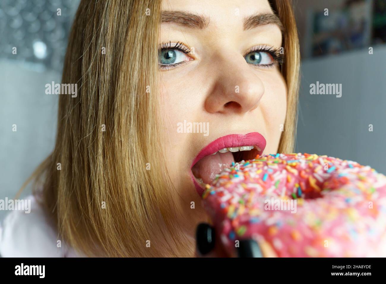 Young woman eating a donut close-up selective focus. Wide angle Stock ...