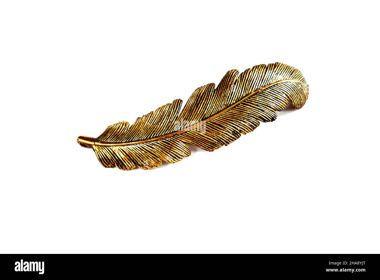 Gold feather plastic isolated on white background close up. Souvenir ...