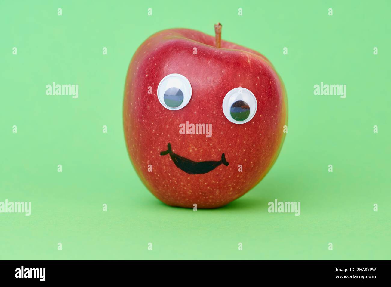 red apple with wiggle eyes on green background Stock Photo - Alamy
