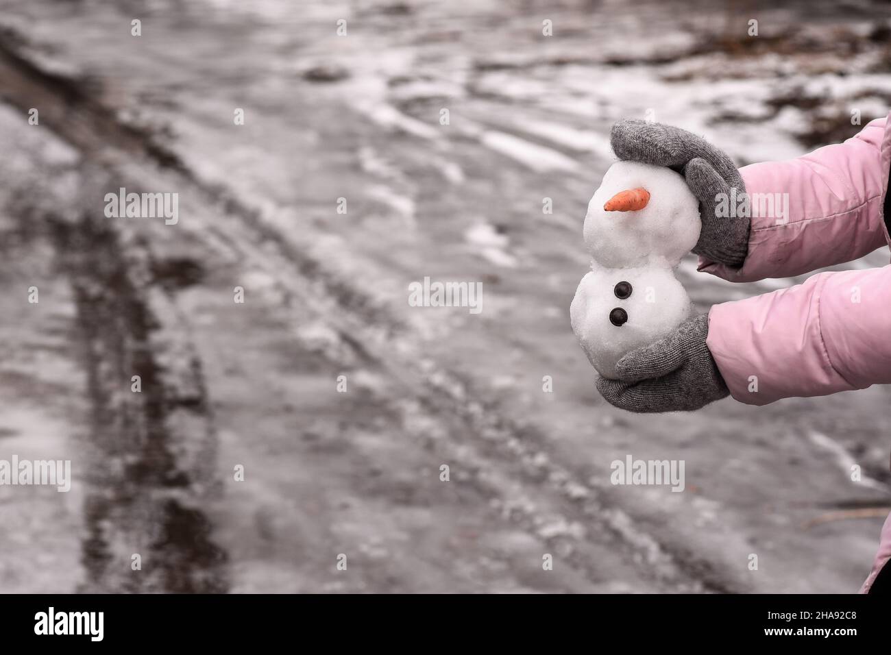 a snowman in mittened hands. arrival of spring Stock Photo - Alamy