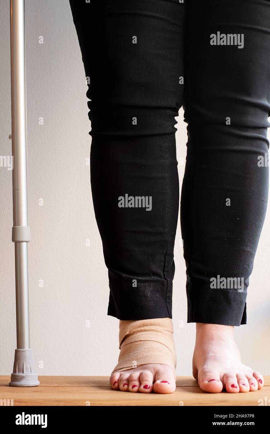 Legs of a person with one foot wrapped with an elastic bandage. Next to ...