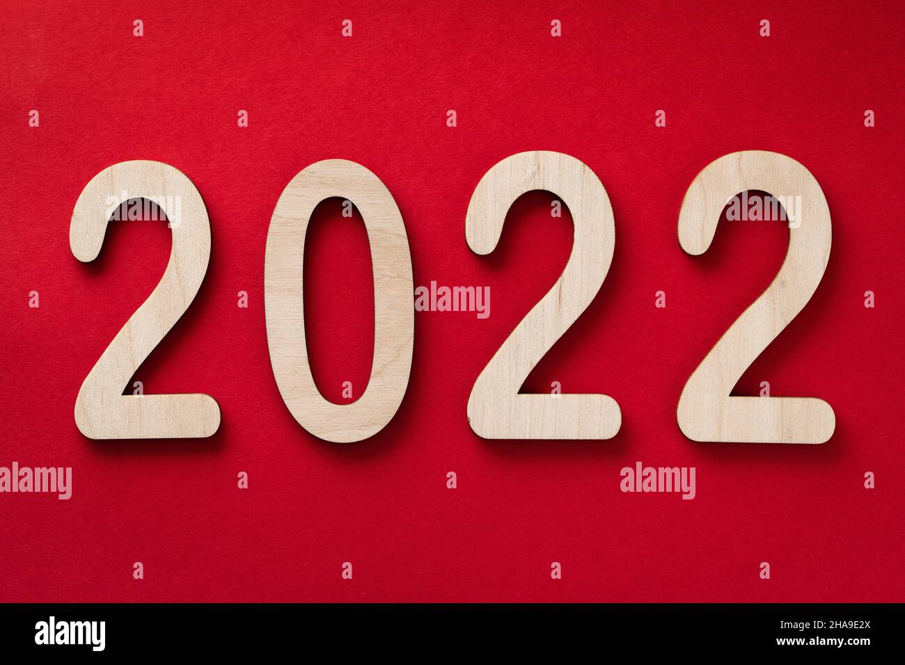 2022 year wooden numbers lying on the red paper background with shadows ...