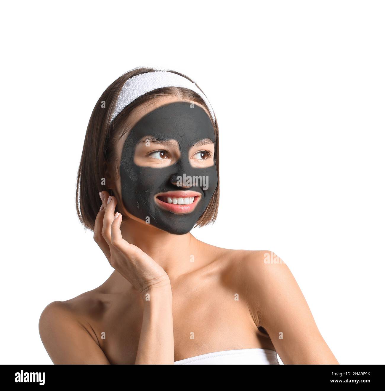 Young woman with activated charcoal mask on her face against white ...