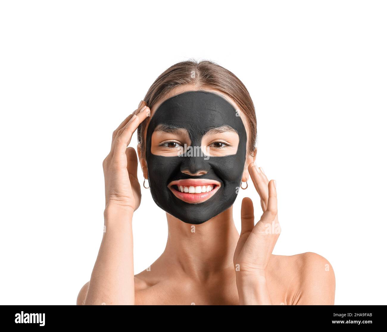 Young woman with activated charcoal mask on her face against white ...