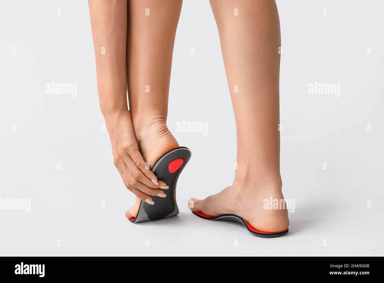 Woman fitting orthopedic insole on light background Stock Photo - Alamy
