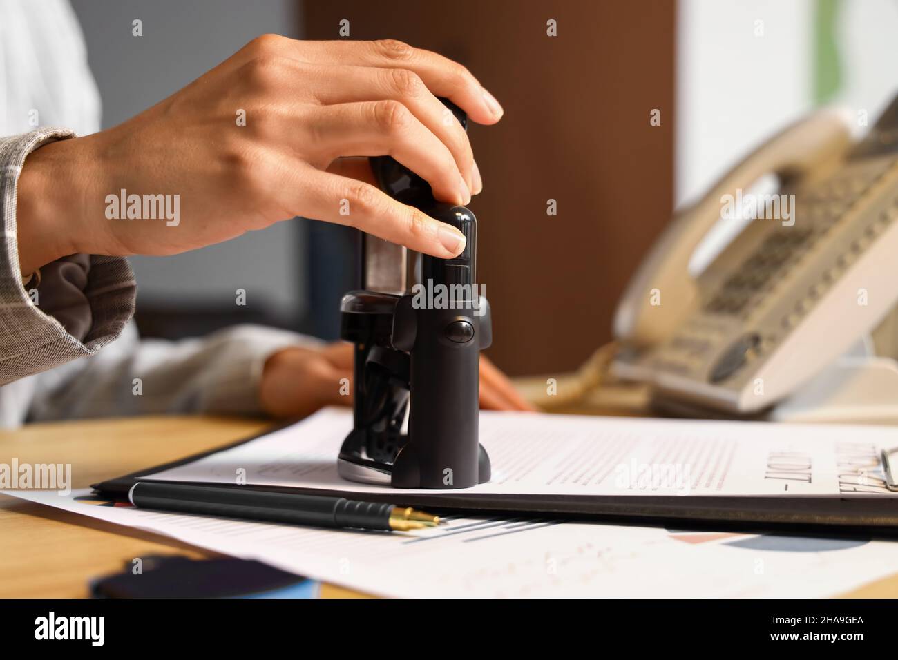 Female notary public attaching seal to document in office, closeup ...
