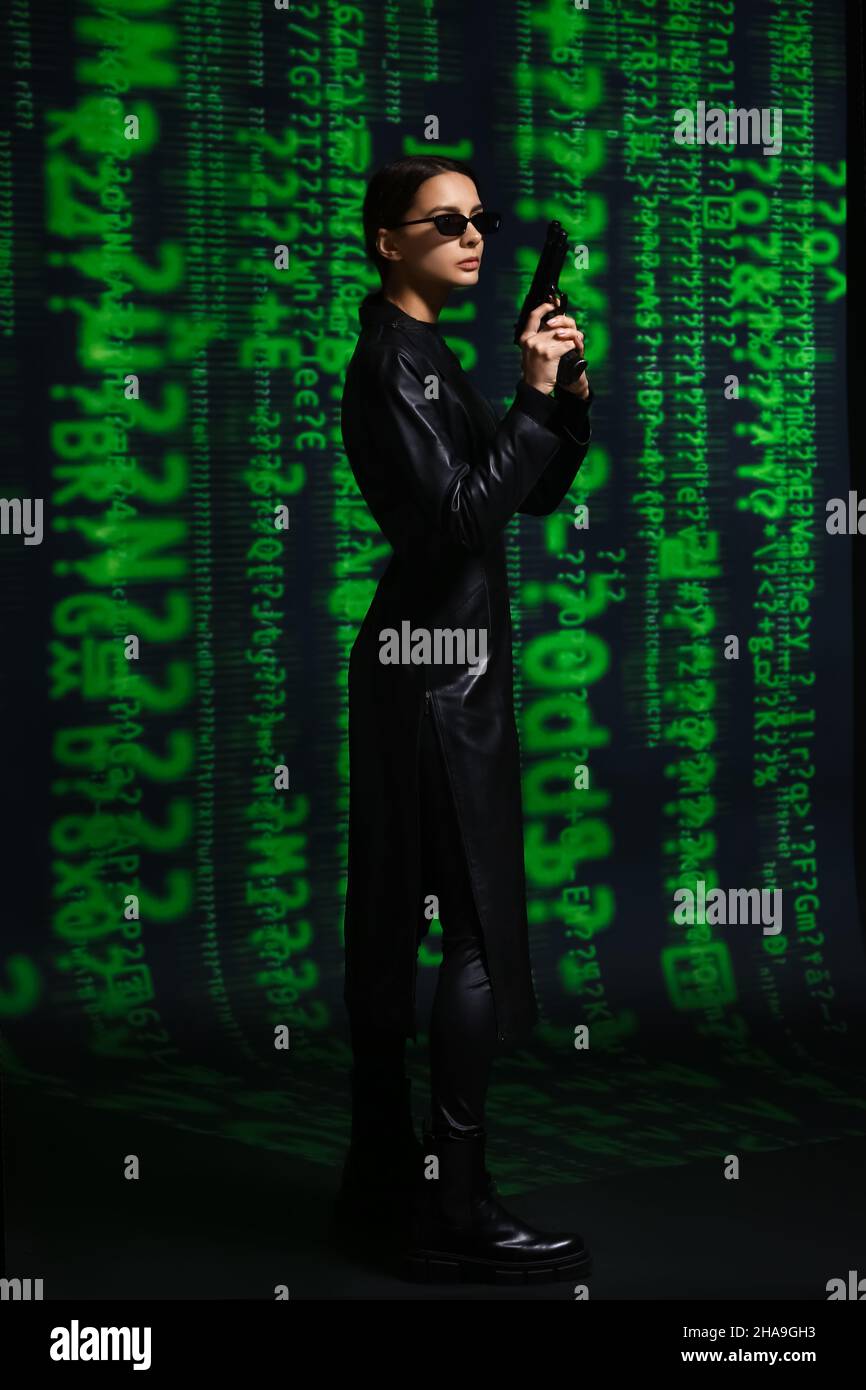 Woman with gun dressed in matrix style on dark background Stock Photo ...