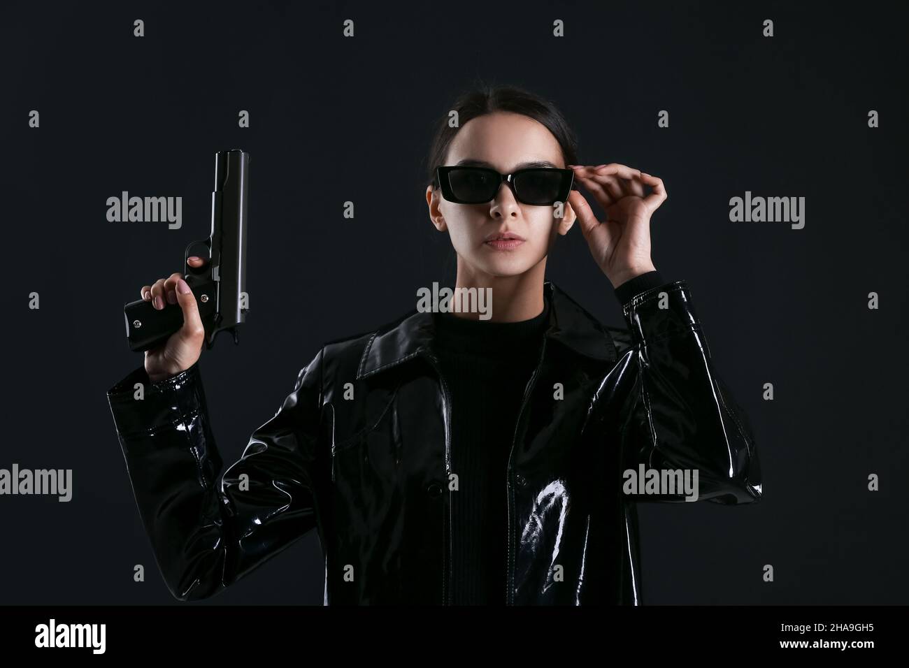 Woman with gun dressed in matrix style on dark background Stock Photo ...