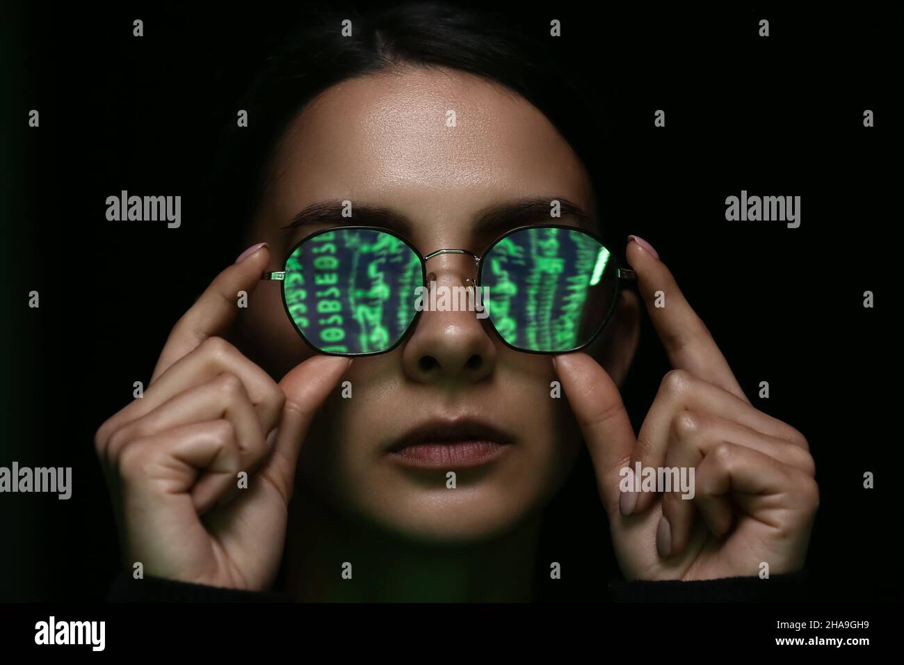 Woman with reflection of matrix code in her tinted glasses on dark ...