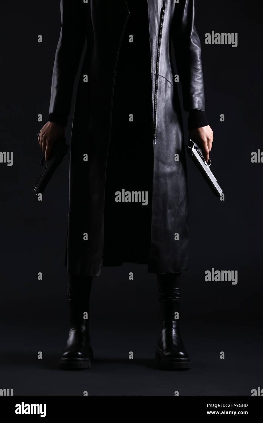 Woman with guns dressed in matrix style on dark background Stock Photo ...