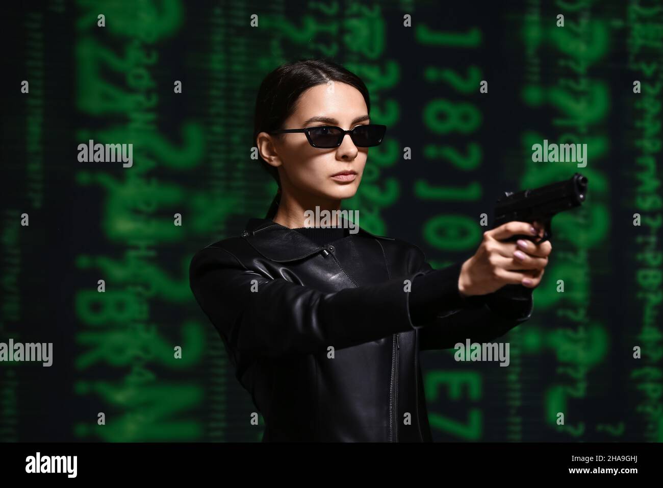 Woman with gun dressed in matrix style on dark background Stock Photo ...