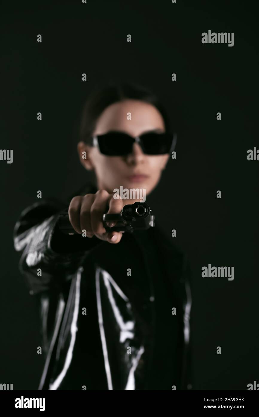 Woman with gun dressed in matrix style on dark background Stock Photo ...