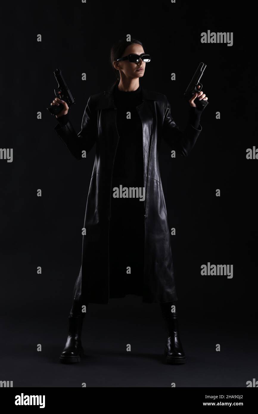 Woman with guns dressed in matrix style on dark background Stock Photo ...