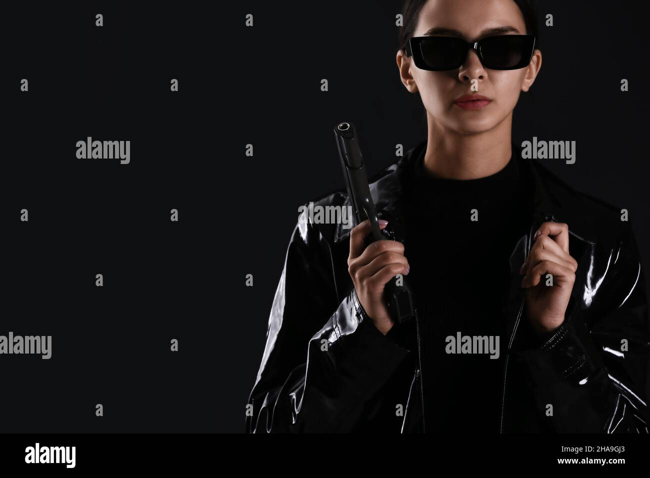 Woman with guns dressed in matrix style on dark background Stock Photo ...