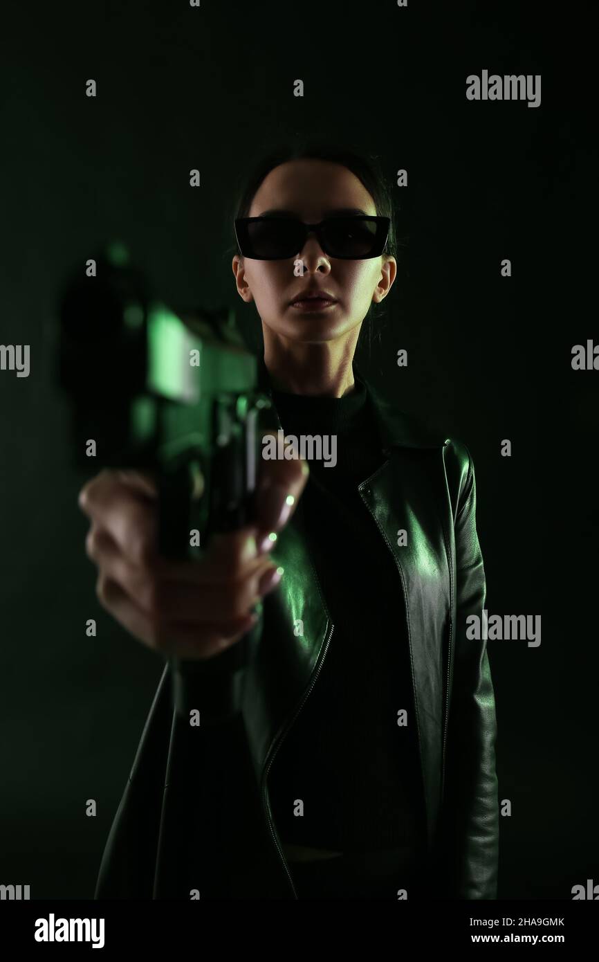 Woman with gun dressed in matrix style on dark background Stock Photo ...