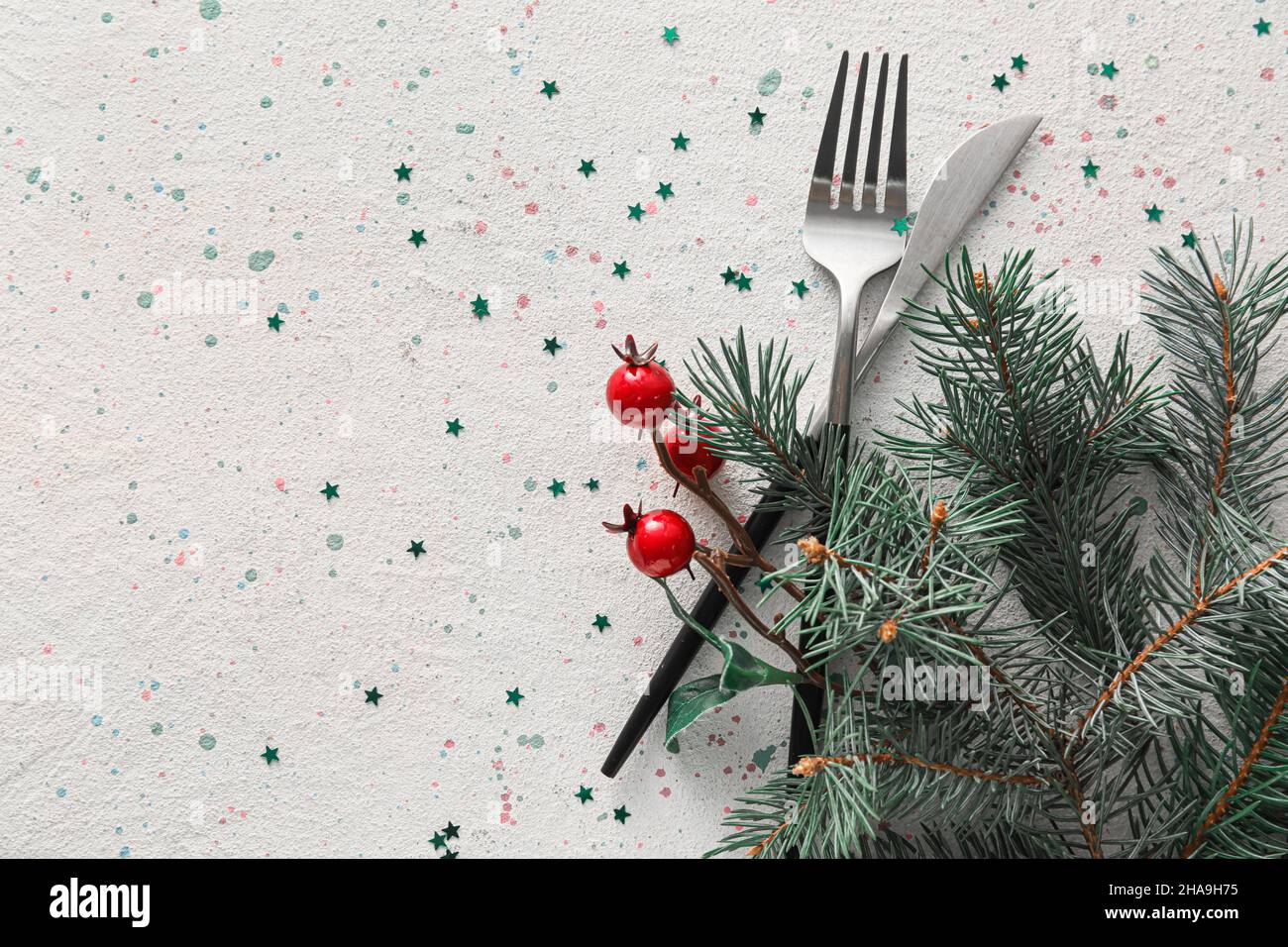 Beautiful cutlery, berries and fir branches on light background Stock ...