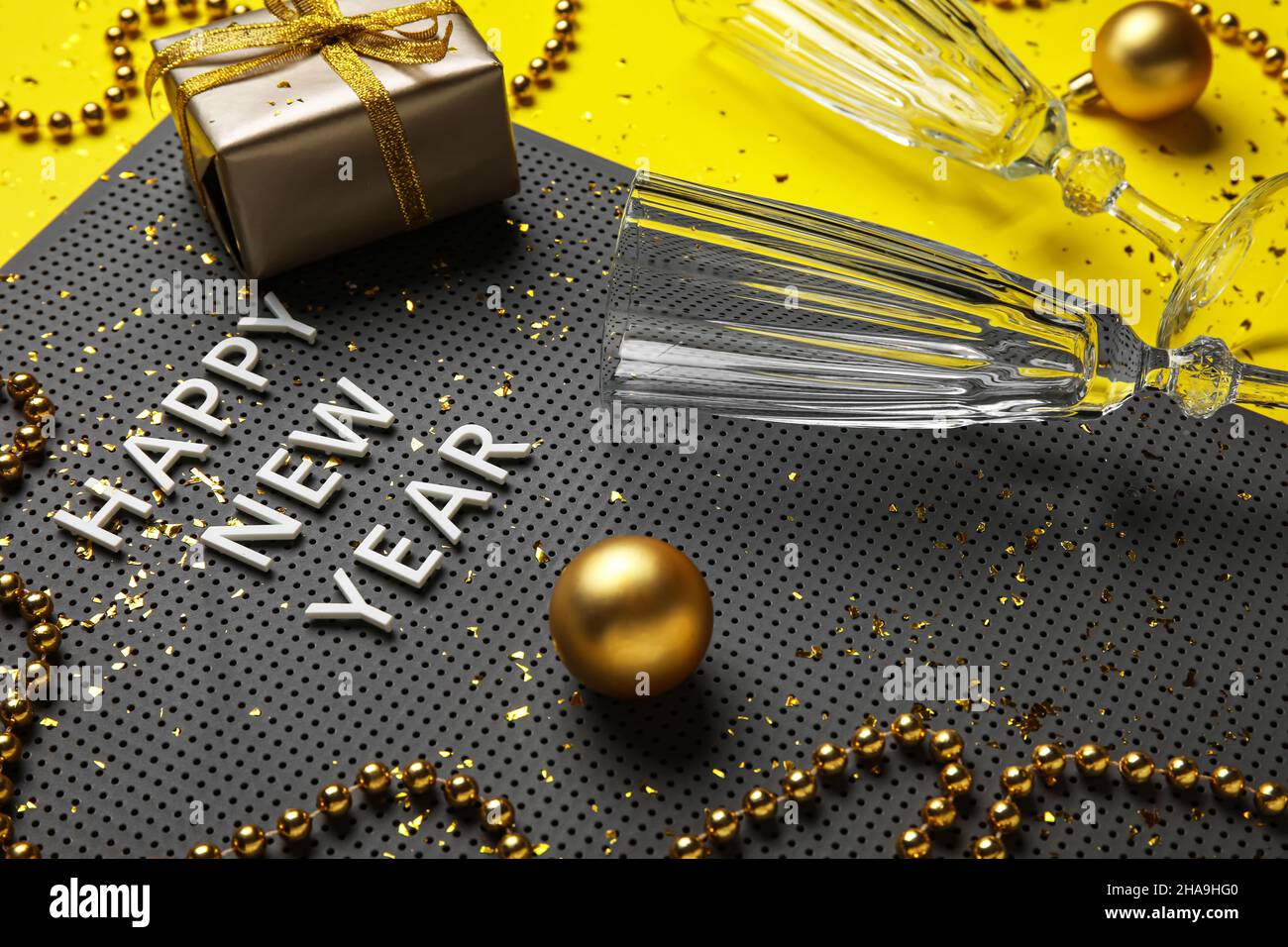 Board with text HAPPY NEW YEAR, glasses, gift boxes and Christmas decor ...