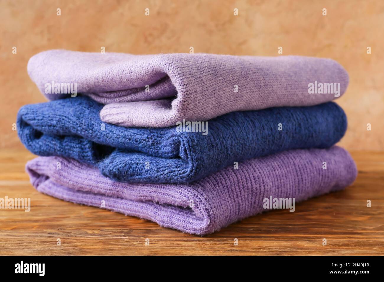 Stack of different cozy sweaters on wooden table Stock Photo - Alamy