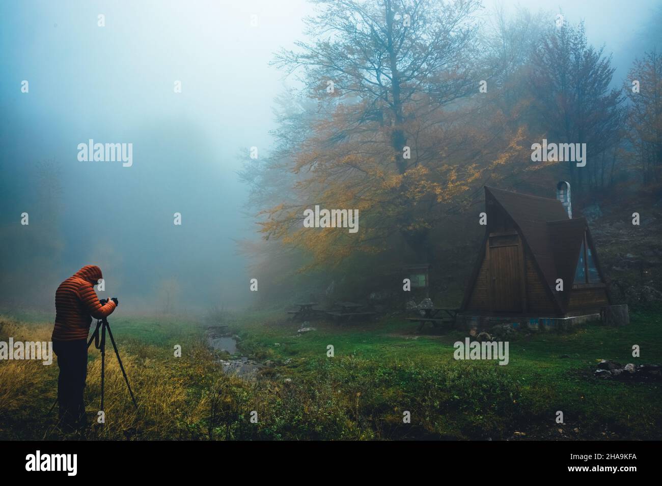Wooden triangle hut in the mountains forest. Autumn colors. Dense mist ...