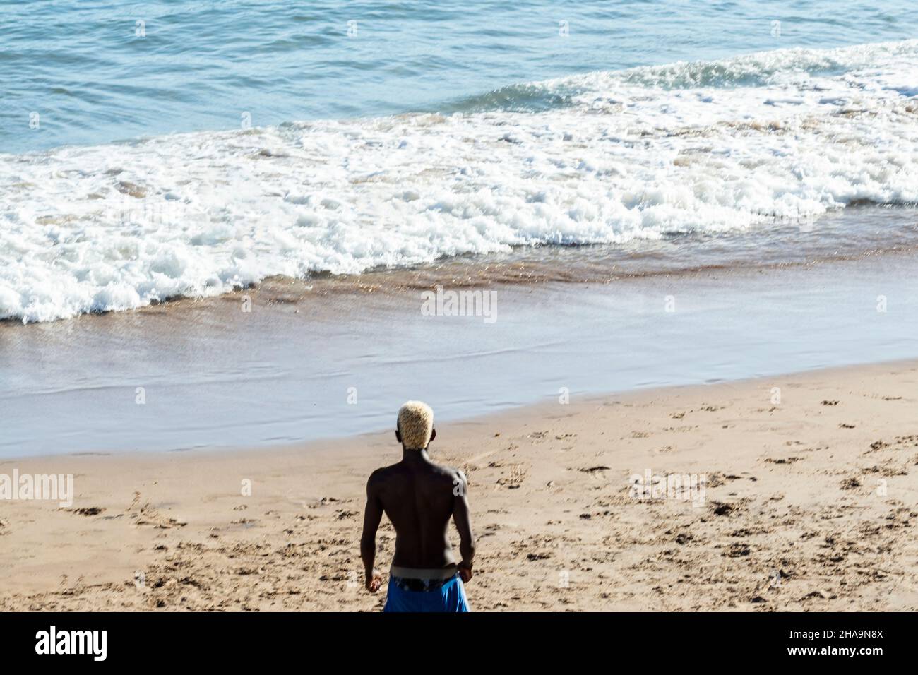 Young model playing sand football on the beach under strong summer sun ...