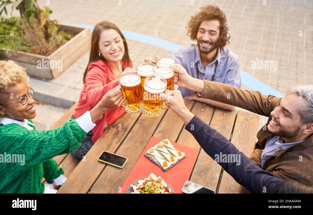 Happy multi ethnic friends drinking beer at terrace outdoors. The focus ...