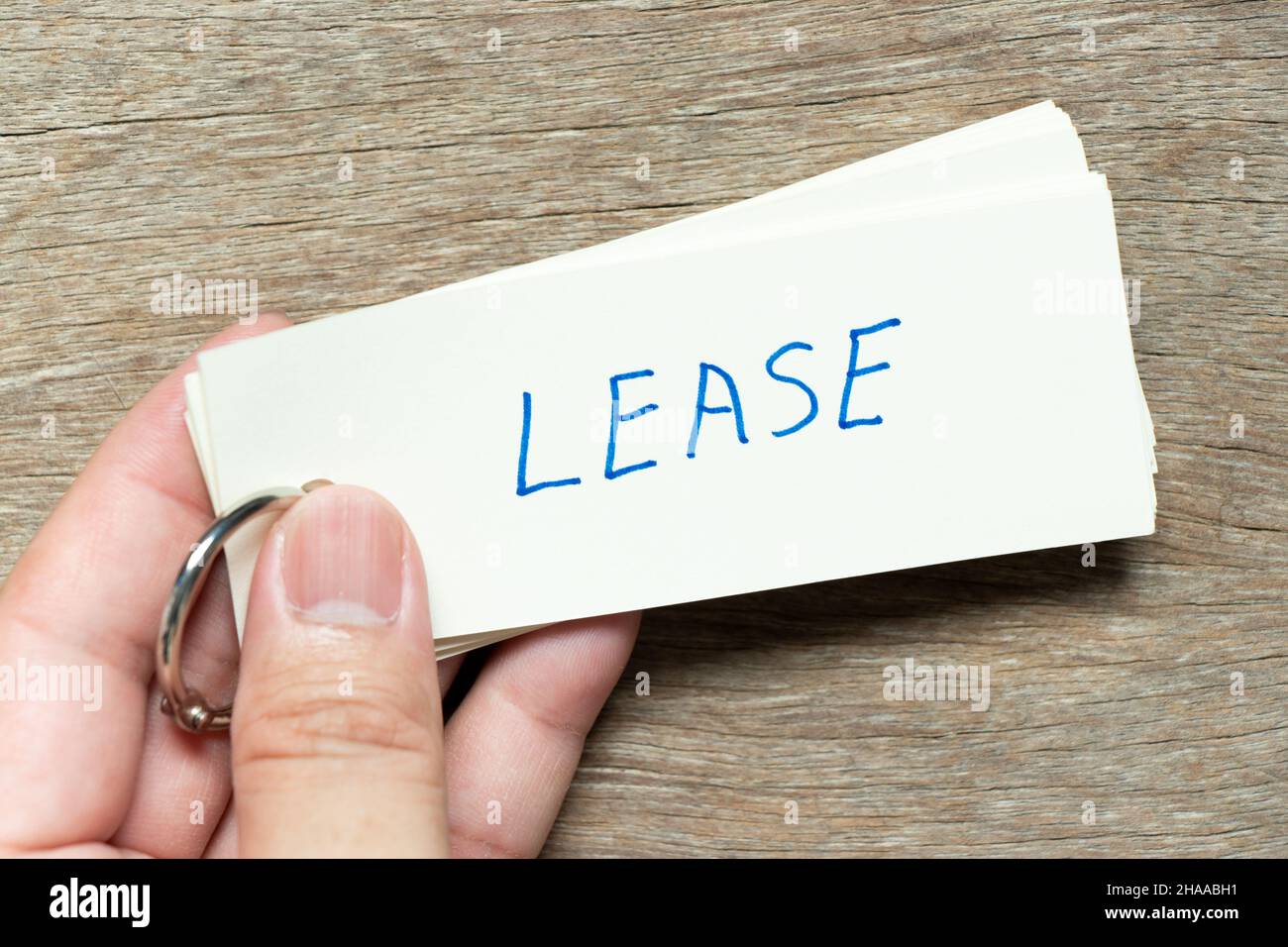 Man hold the flash card with handwriting word lease on wood background ...