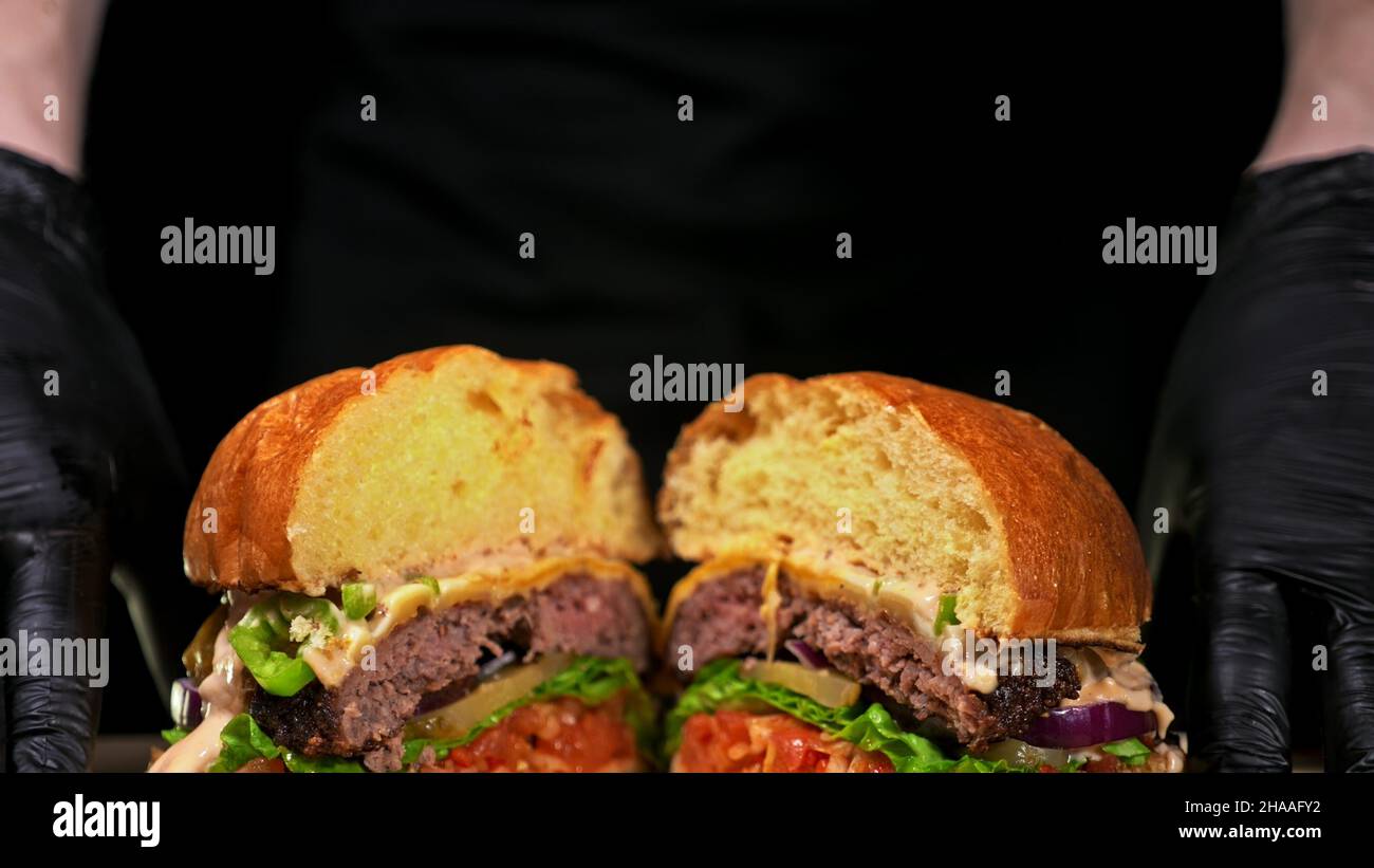 Cut craft burger is cooking on black background. Consist: red sauce ...